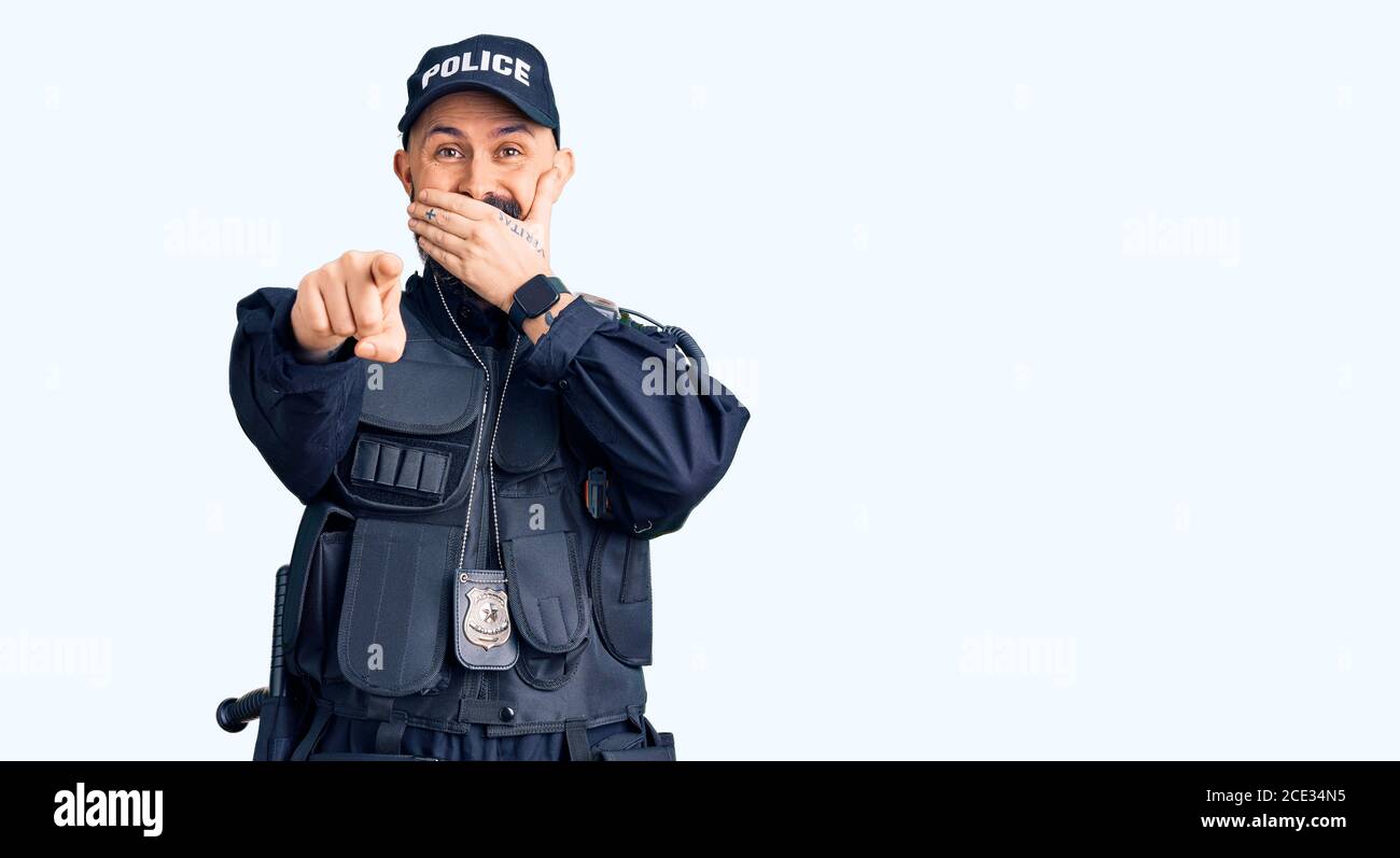 Young handsome man wearing police uniform laughing at you, pointing ...