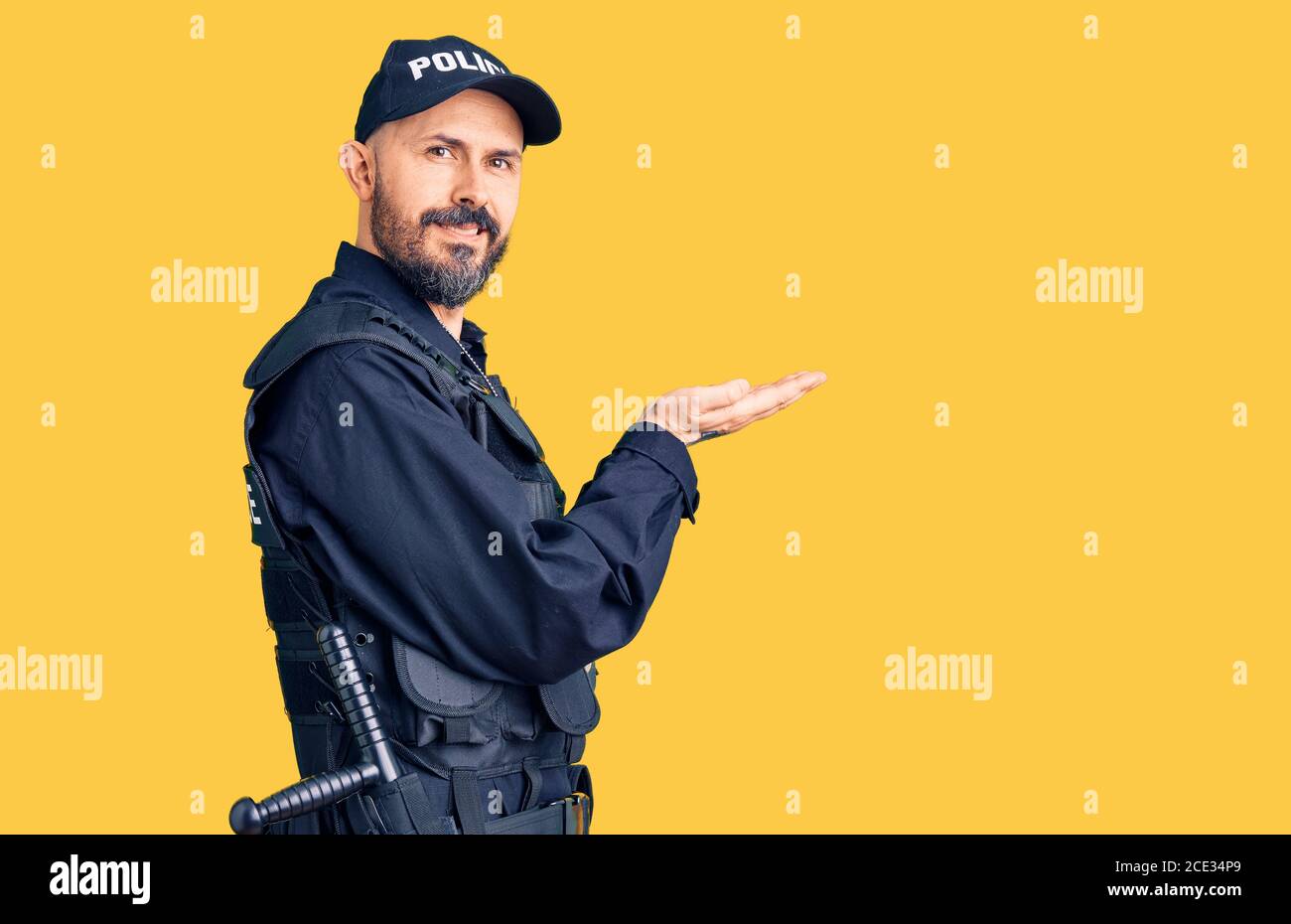 Young handsome man wearing police uniform pointing aside with hands ...