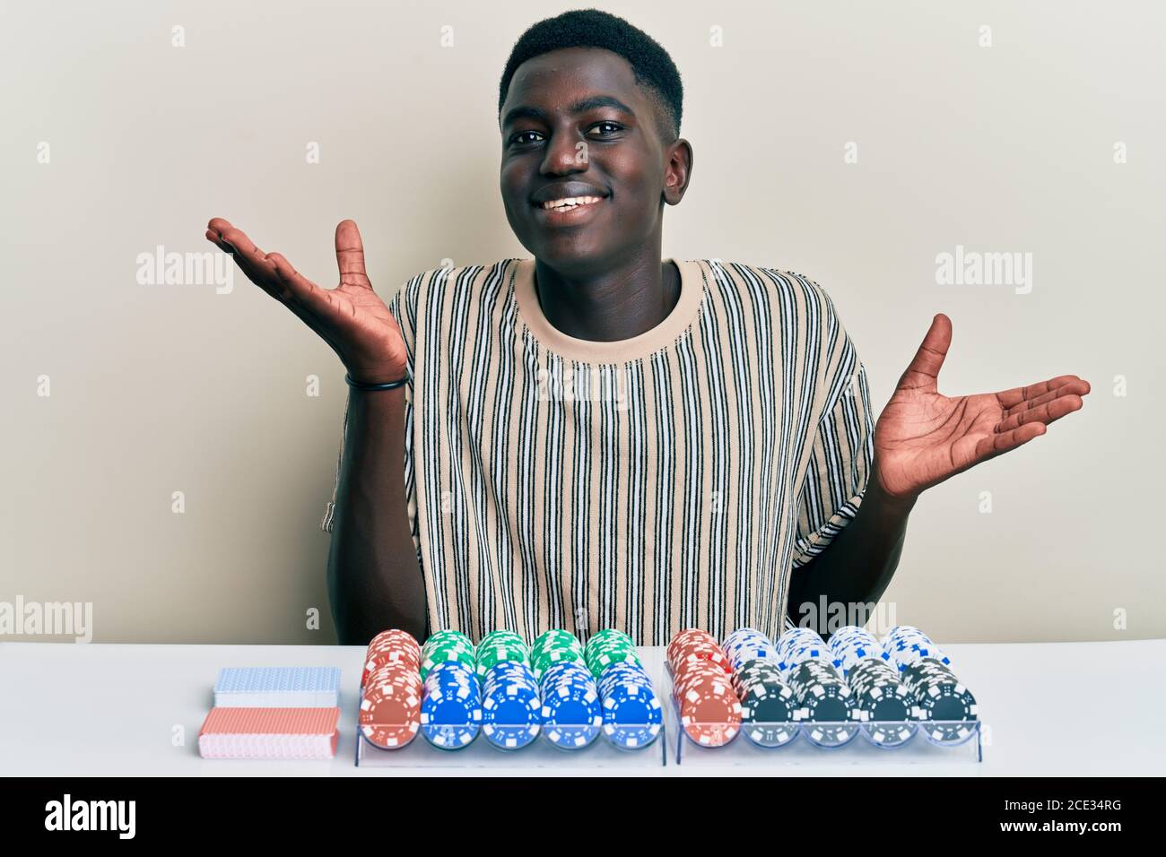 Young african american man sitting on the table with poker chips and ...