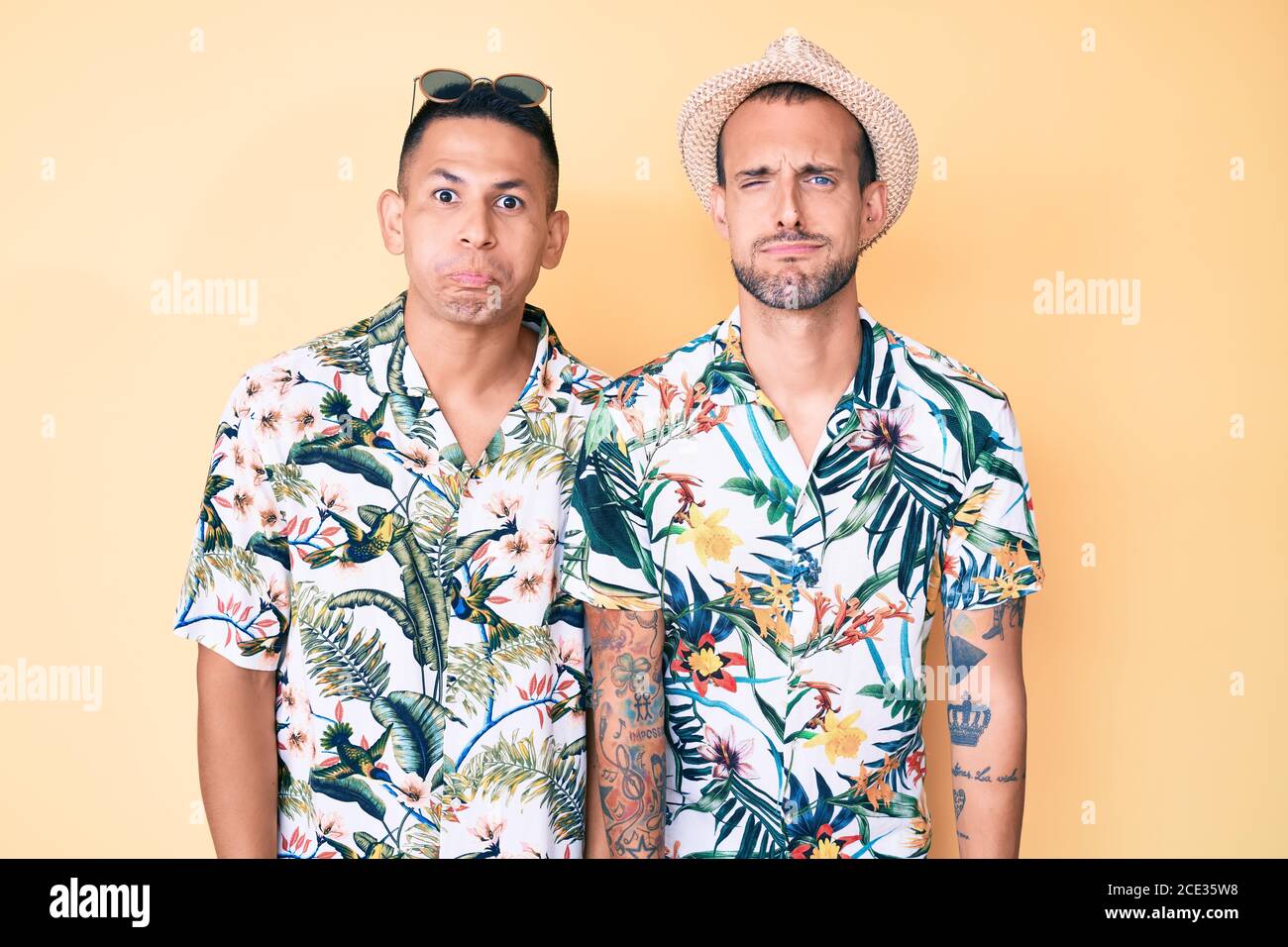 Young gay couple of two men wearing summer hat and hawaiian shirt ...
