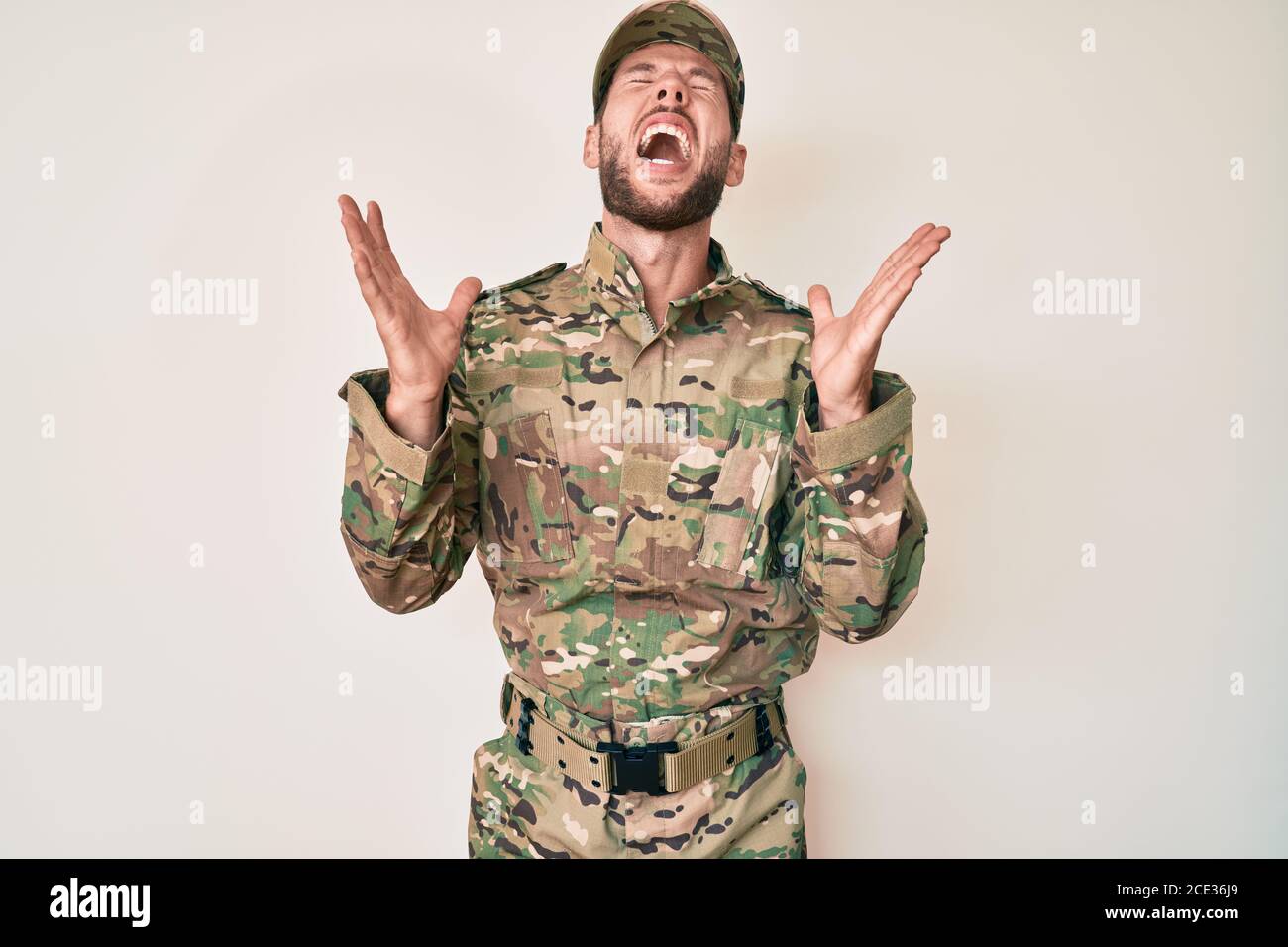 Young caucasian man wearing camouflage army uniform celebrating mad and ...