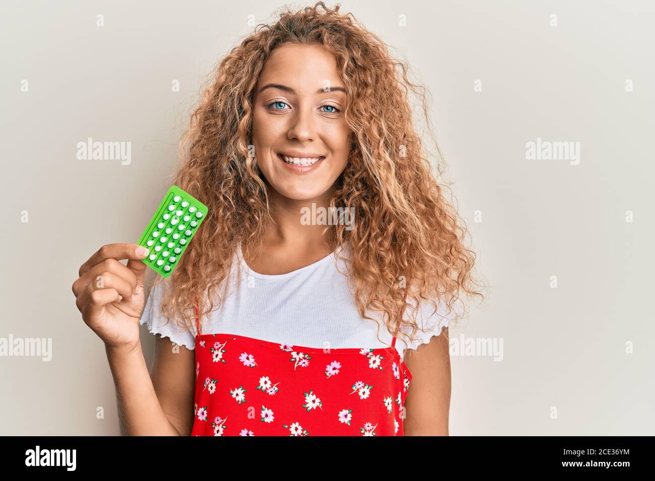 Beautiful caucasian teenager girl holding birth control pills looking ...