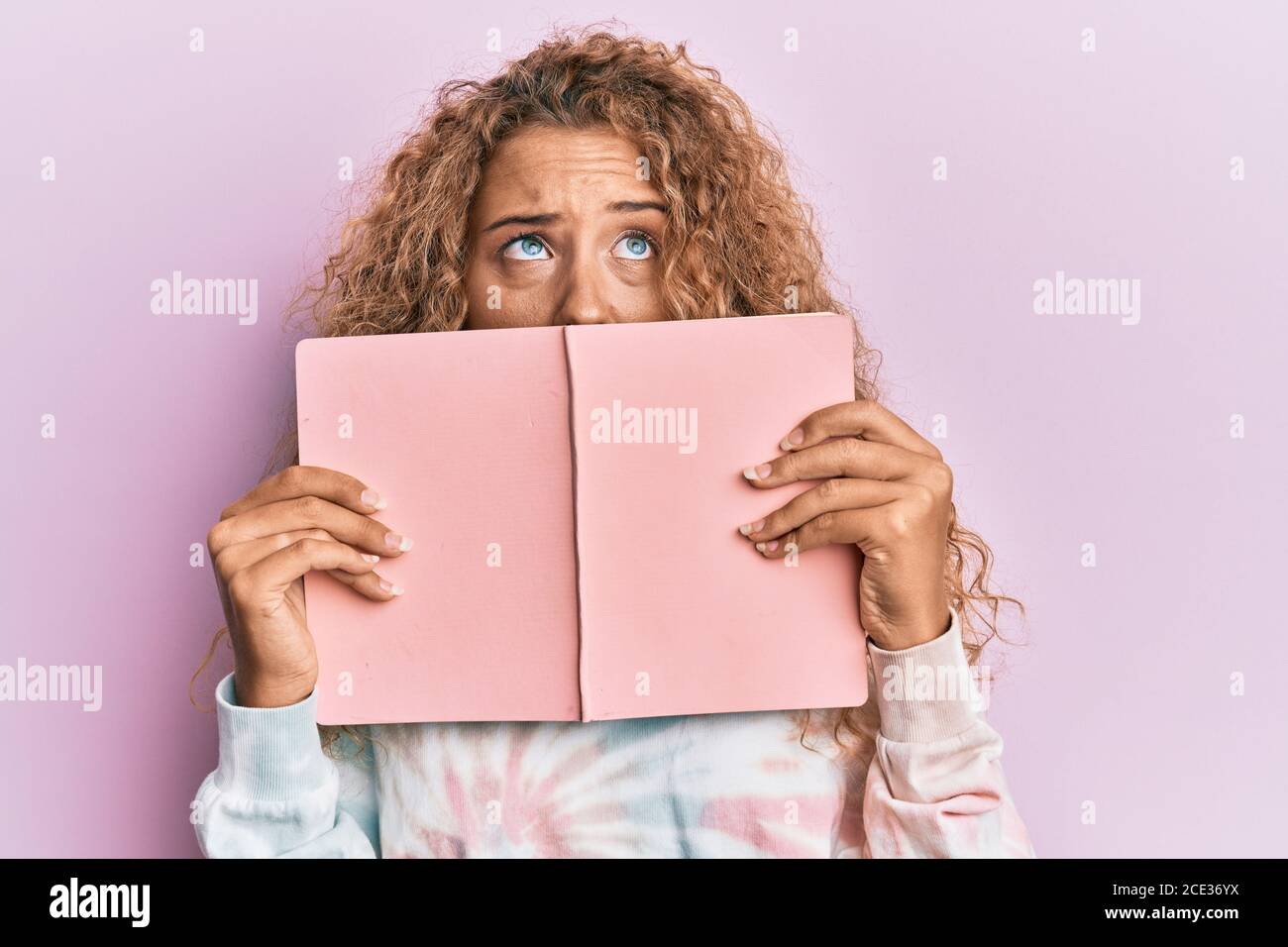 Beautiful caucasian teenager girl reading a book covering face angry ...