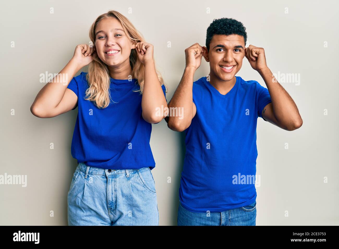 Young interracial couple wearing casual clothes smiling pulling ears ...