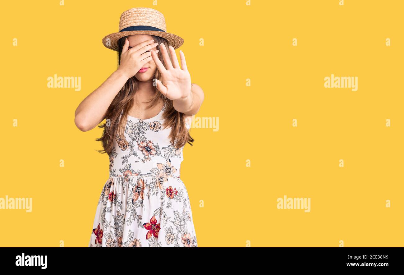 Beautiful caucasian young woman wearing summer hat covering eyes with ...