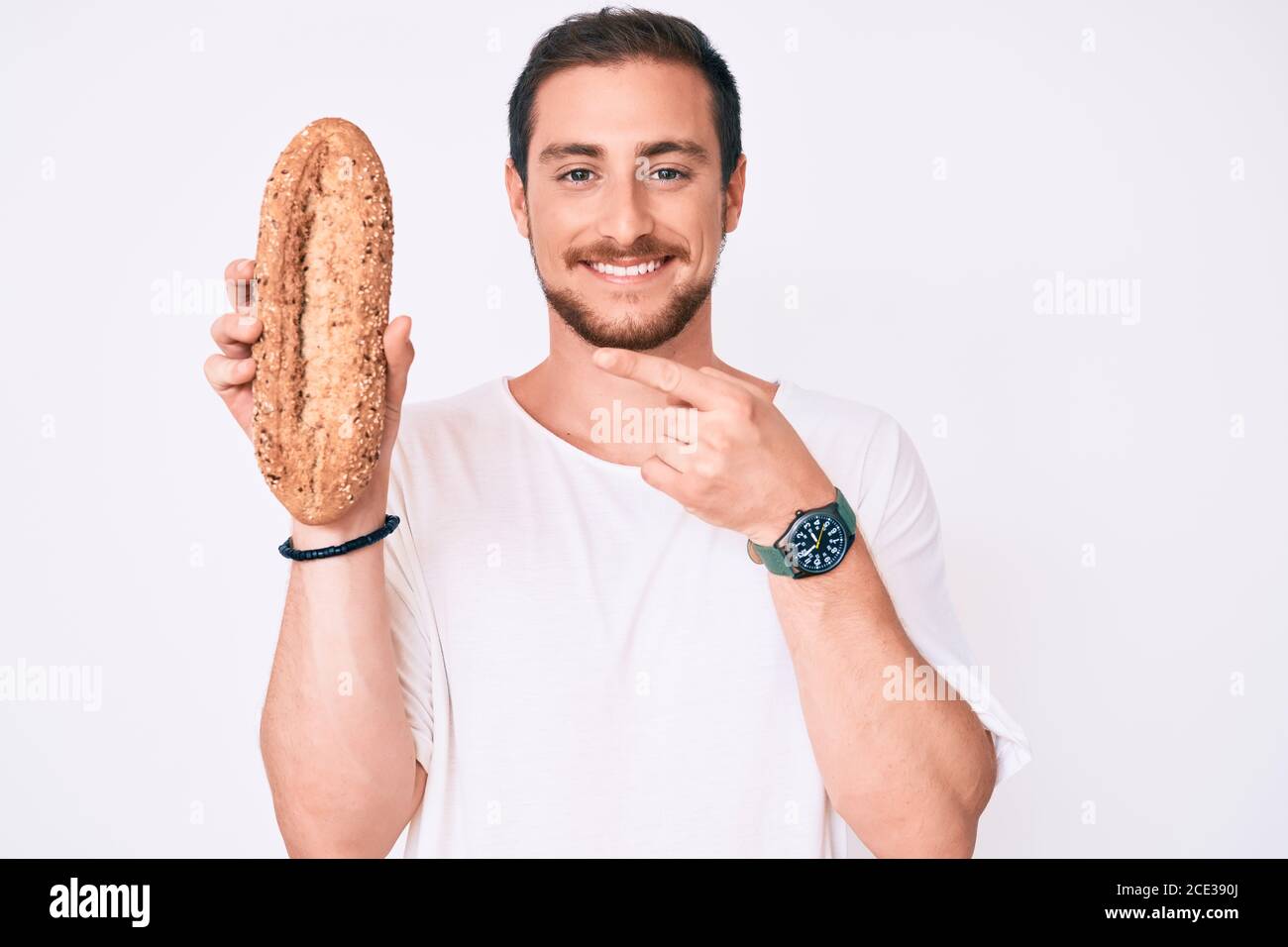 Young handsome man holding wholemeal bread smiling happy pointing with ...