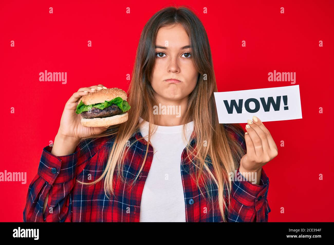 Beautiful caucasian woman eating a tasty classic burger holding wow ...