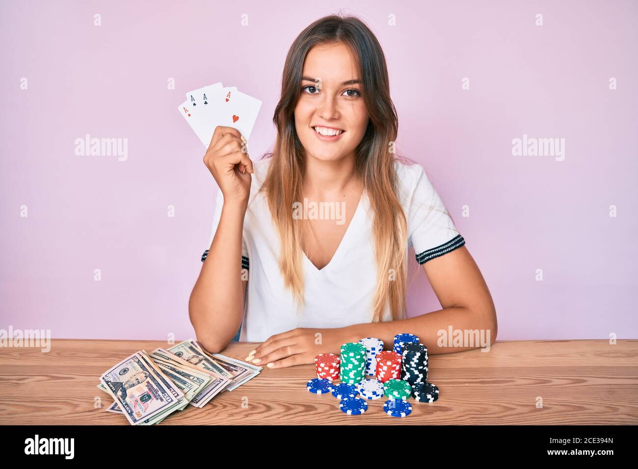 Beautiful caucasian woman playing poker holding cards looking positive ...