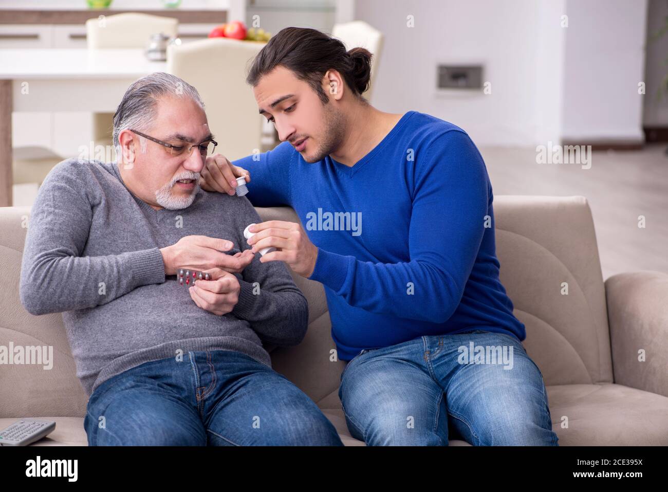 Young man looking after his sick father at home Stock Photo - Alamy