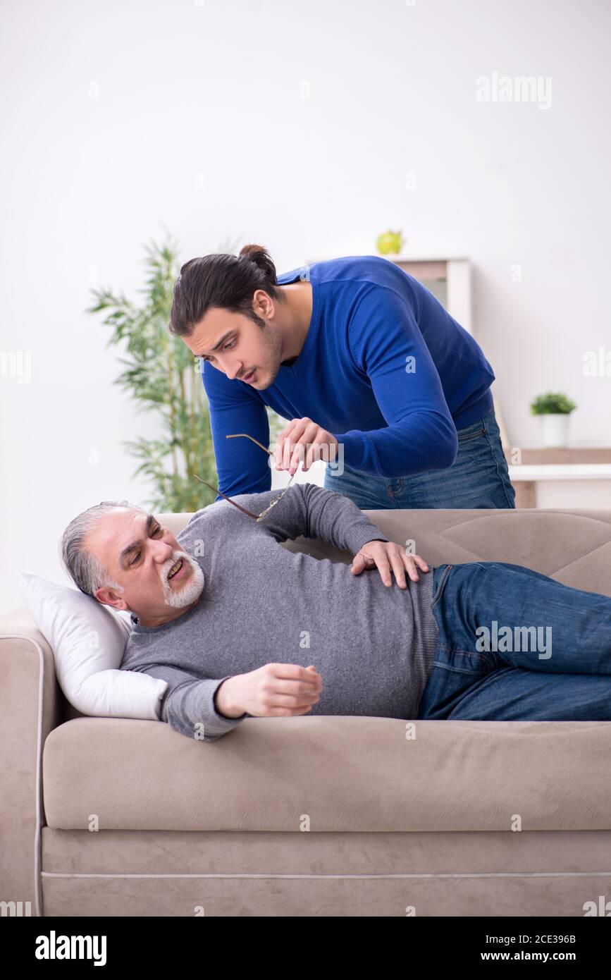 Young man looking after his sick father at home Stock Photo - Alamy