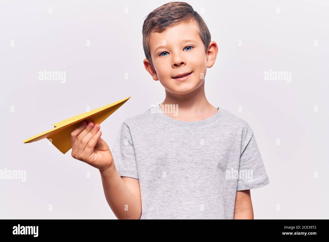 Cute blond kid holding paper airplane looking positive and happy ...