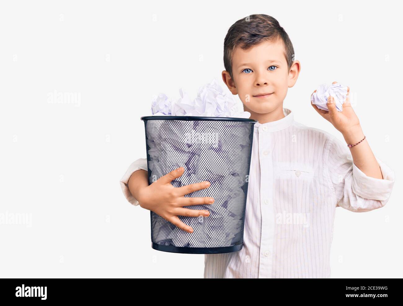 Cute blond kid holding paper bin full of crumpled papers looking ...