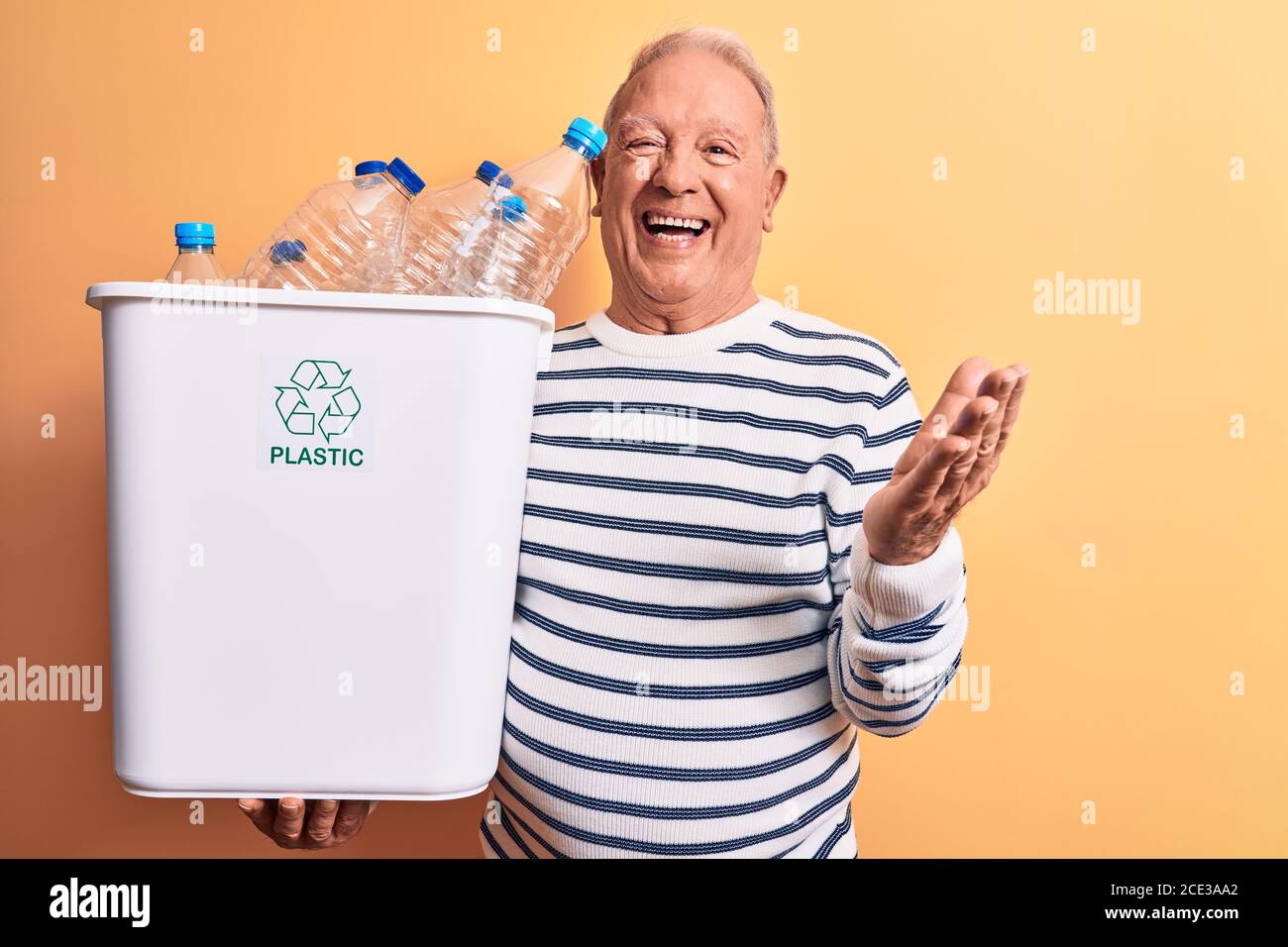 Senior handsome grey-haired man recycling holding wastebasket full of ...