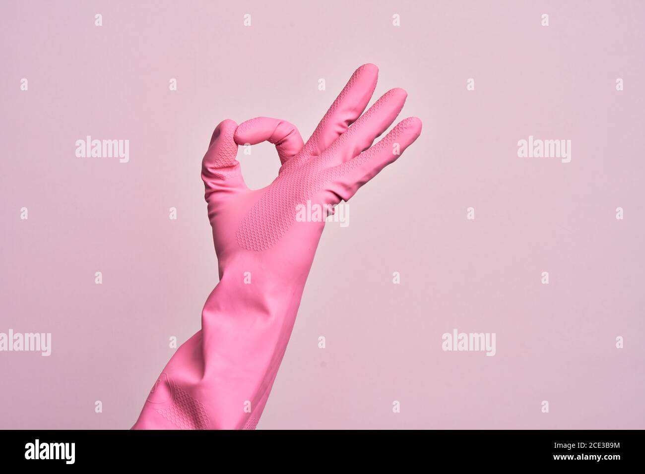 Hand of caucasian young man with cleaning glove over isolated pink ...