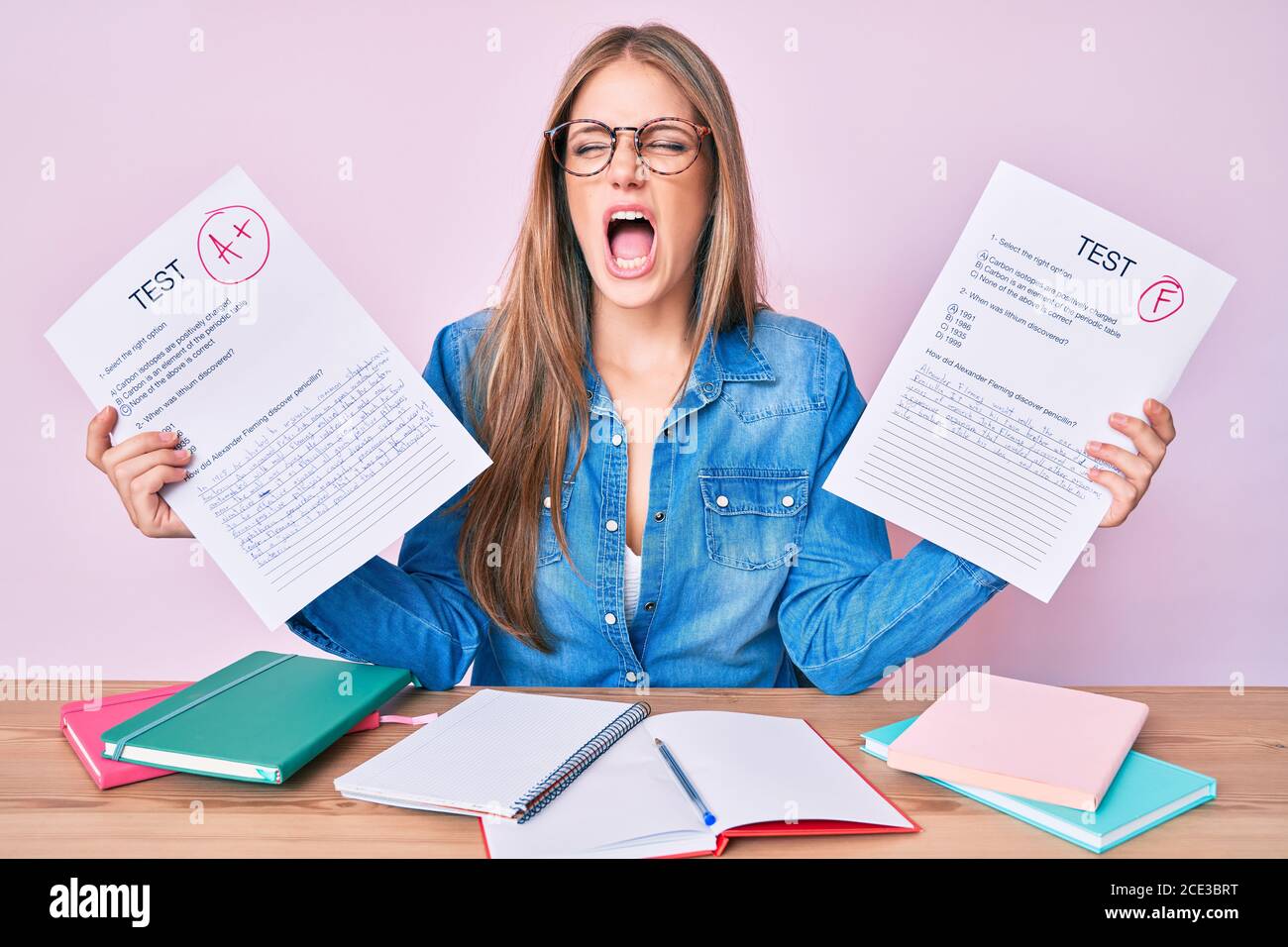 Young blonde girl showing failed and passed exams sitting on the table ...