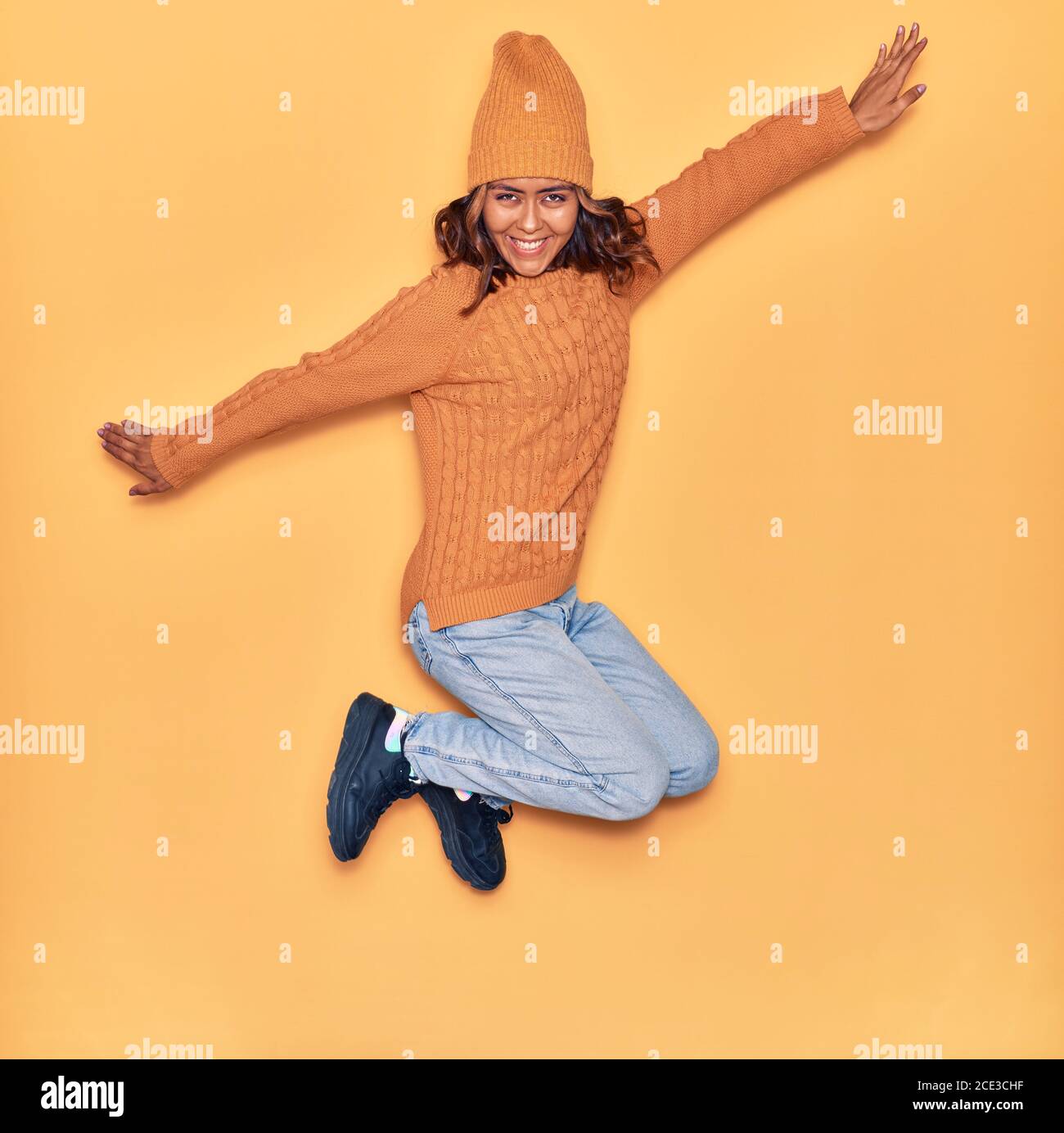 Young beautiful latin woman wearing wool cap and sweater smiling happy ...