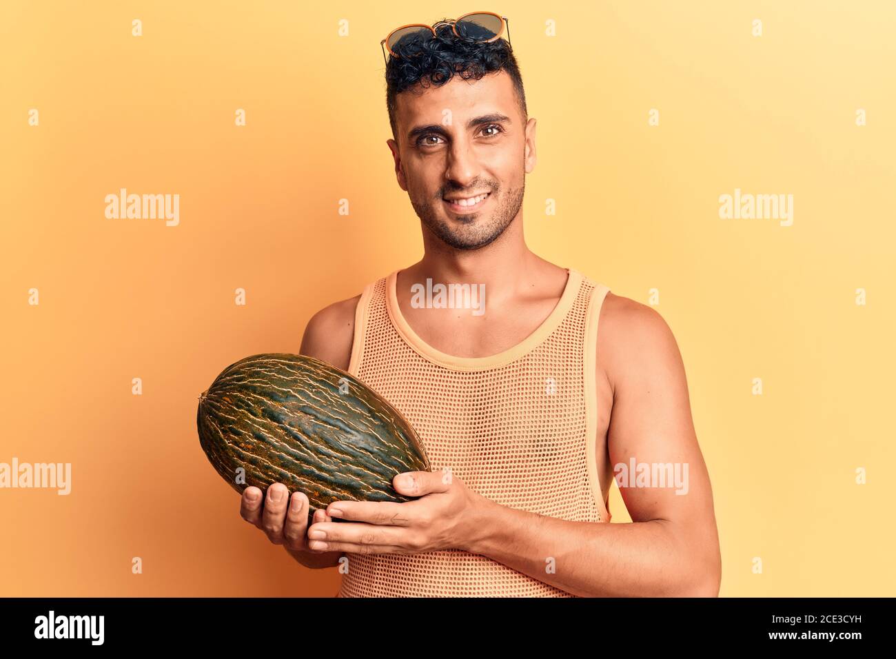 Young hispanic man holding melon looking positive and happy standing ...