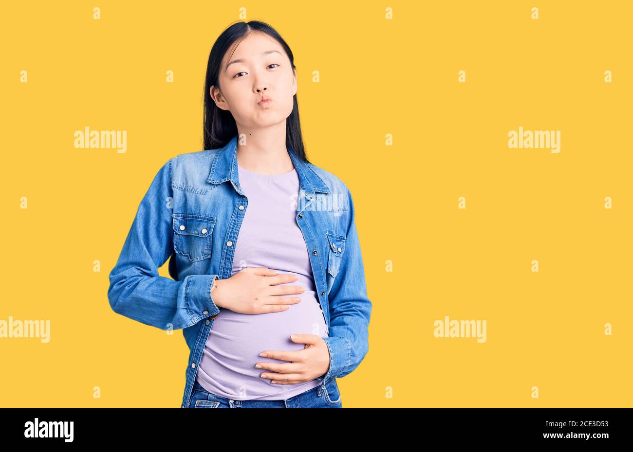 Young beautiful chinese woman pregnant expecting baby puffing cheeks ...