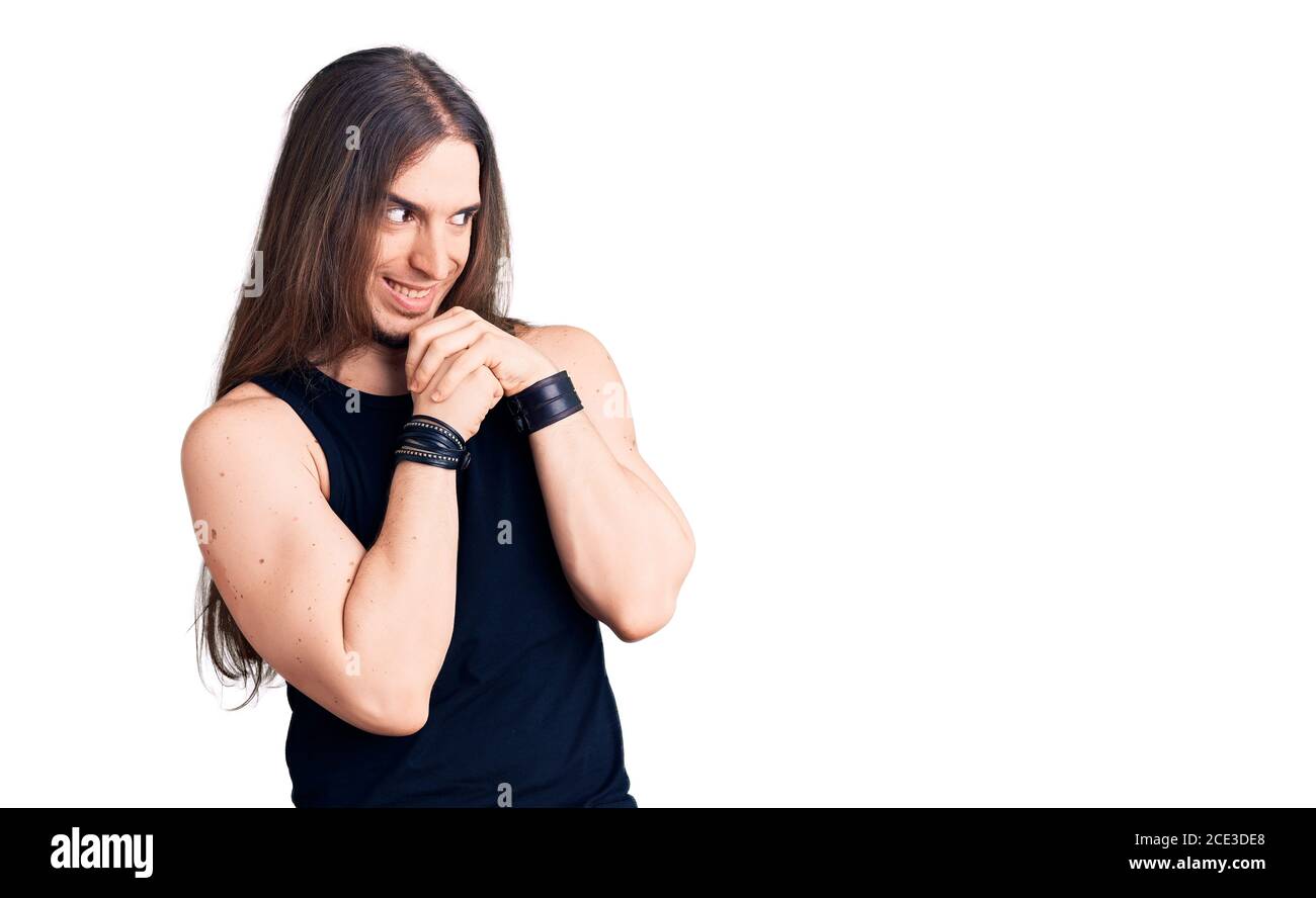 Young adult man with long hair wearing goth style with black clothes ...