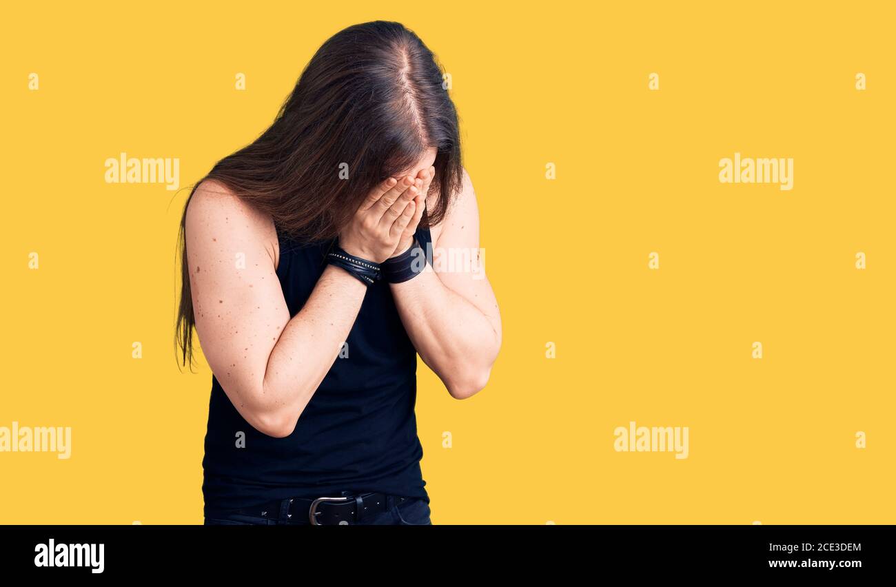 Young adult man with long hair wearing goth style with black clothes ...