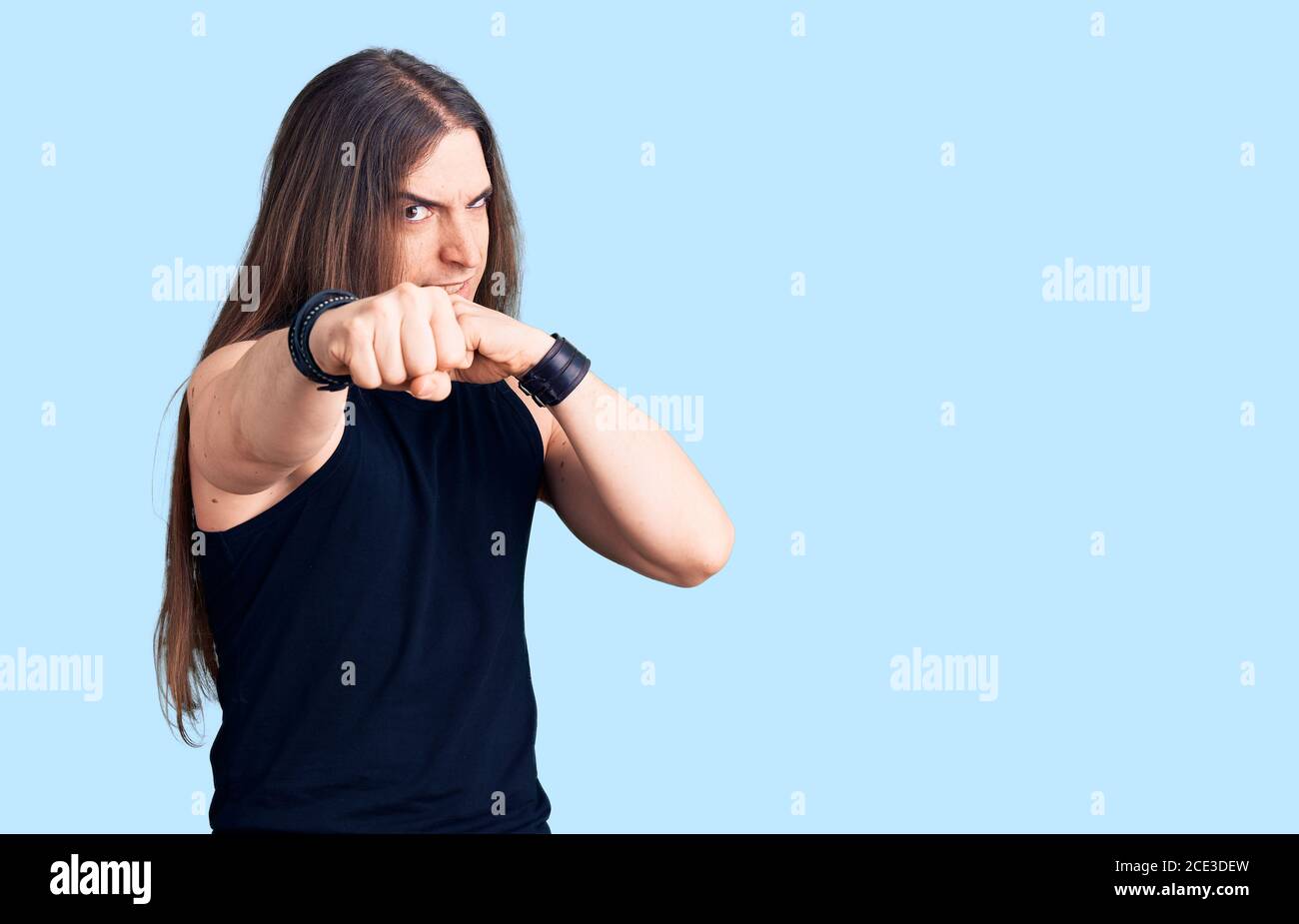 Young adult man with long hair wearing goth style with black clothes ...