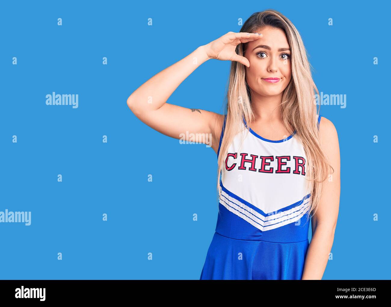 Young beautiful blonde woman wearing cheerleader uniform worried and ...