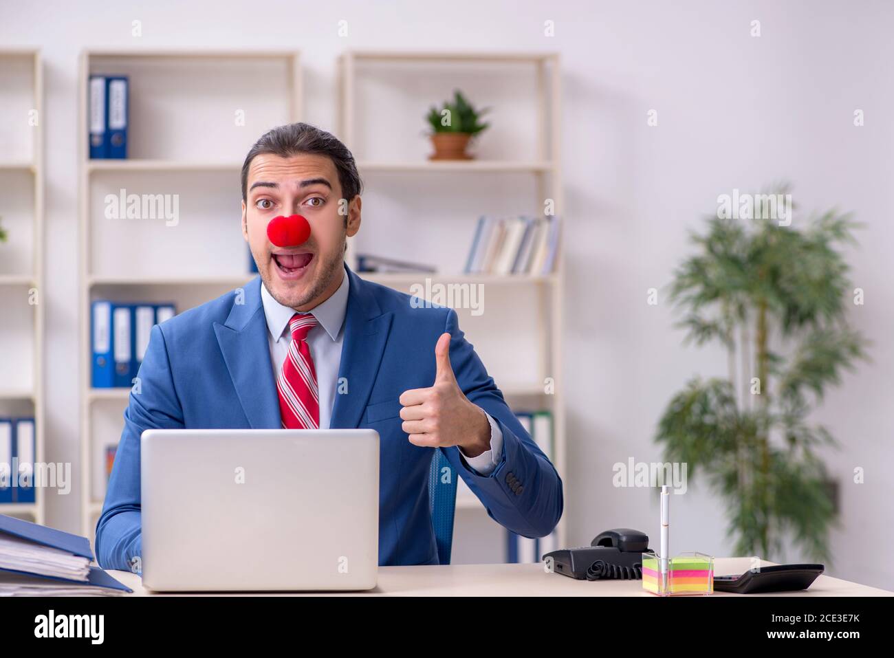 Funny employee clown working in the office room Stock Photo - Alamy