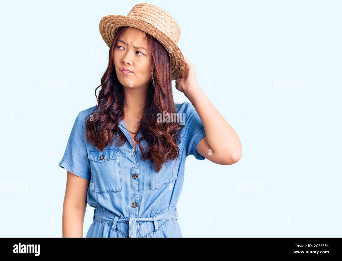 Young beautiful chinese girl wearing summer hat confuse and wondering ...