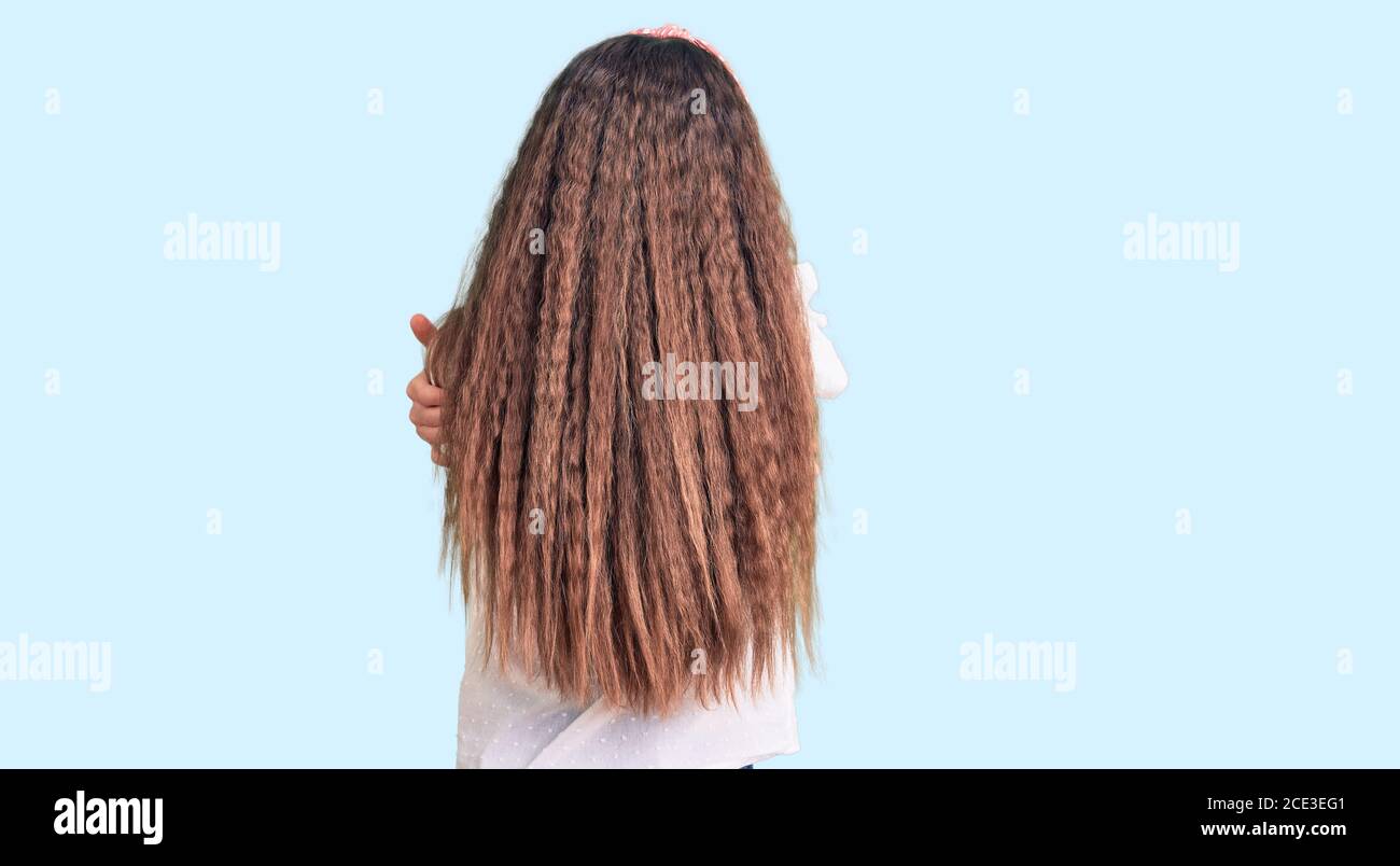 Cute hispanic child girl wearing casual white tshirt hugging oneself ...