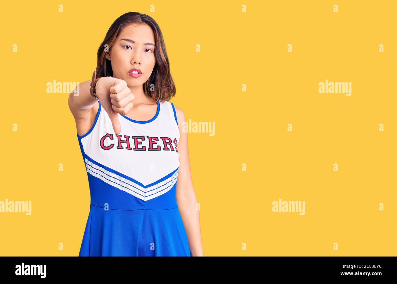 Young beautiful chinese girl wearing cheerleader uniform looking ...