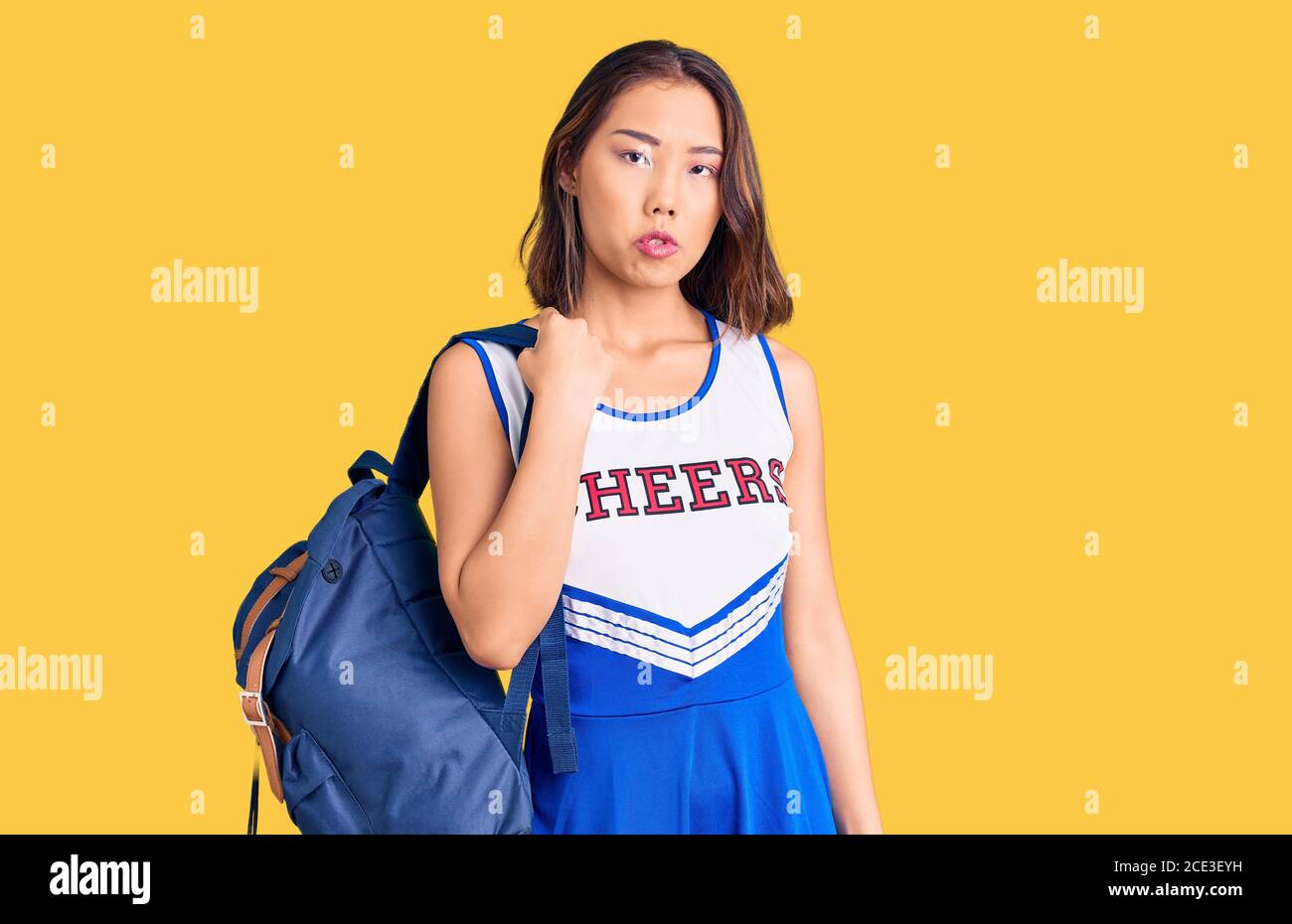 Young beautiful chinese girl wearing cheerleader uniform holding ...