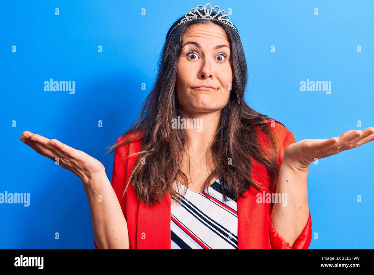 Young beautiful brunette woman wearing princess crown standing over ...