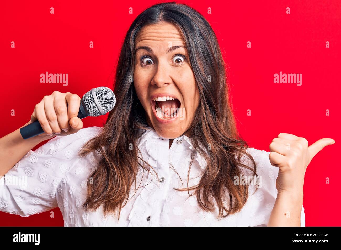 Young beautiful brunette singer woman singing song using microphone ...