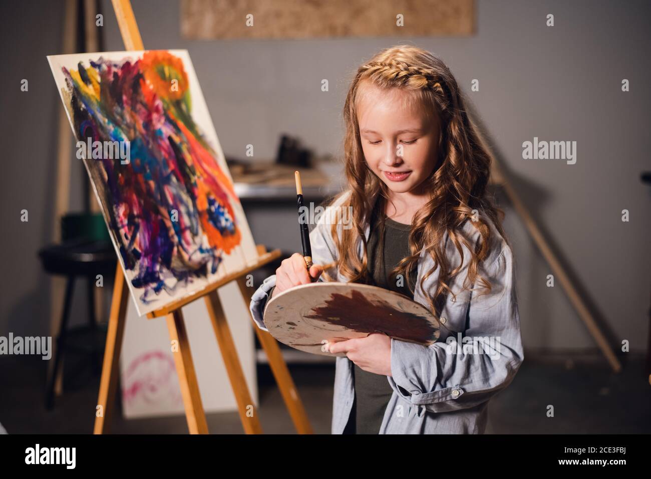 A young cute artist girl is learning to draw in an art workshop. Draws ...