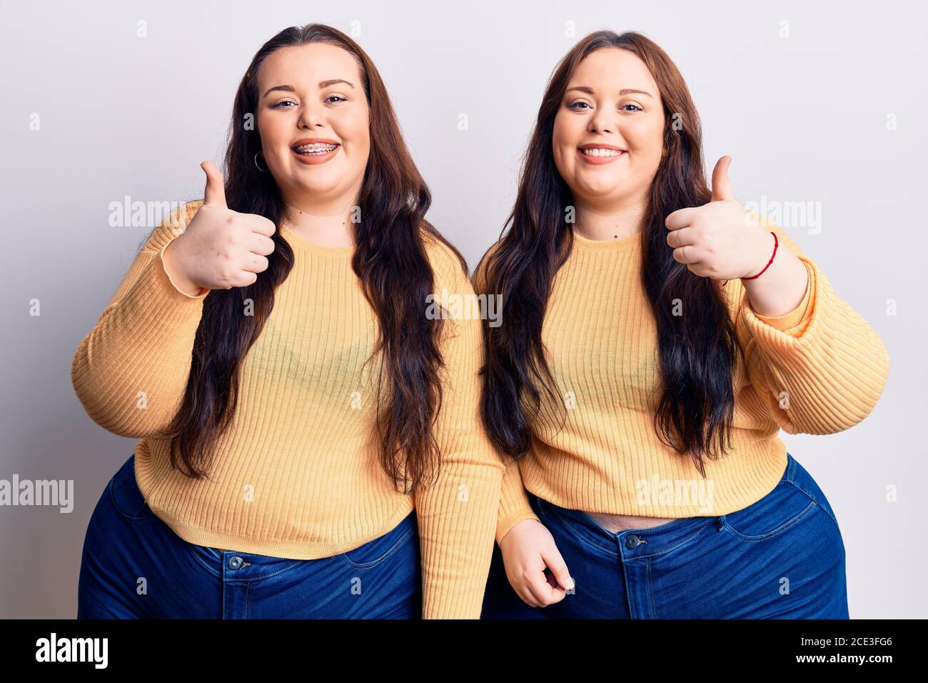 Young plus size twins wearing casual clothes success sign doing ...