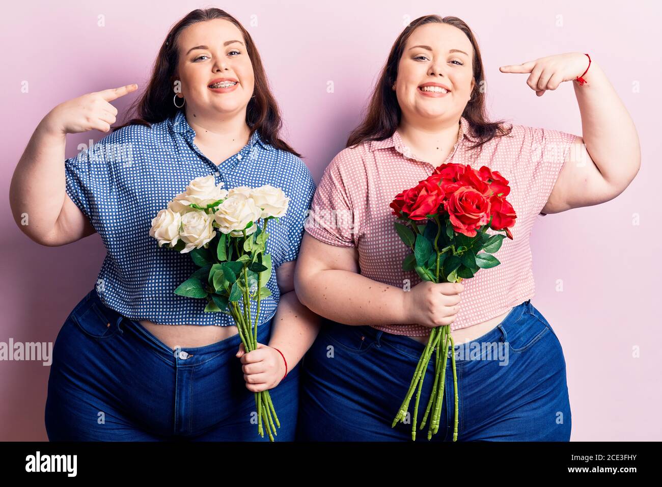 Young plus size twins holding flowers pointing finger to one self ...