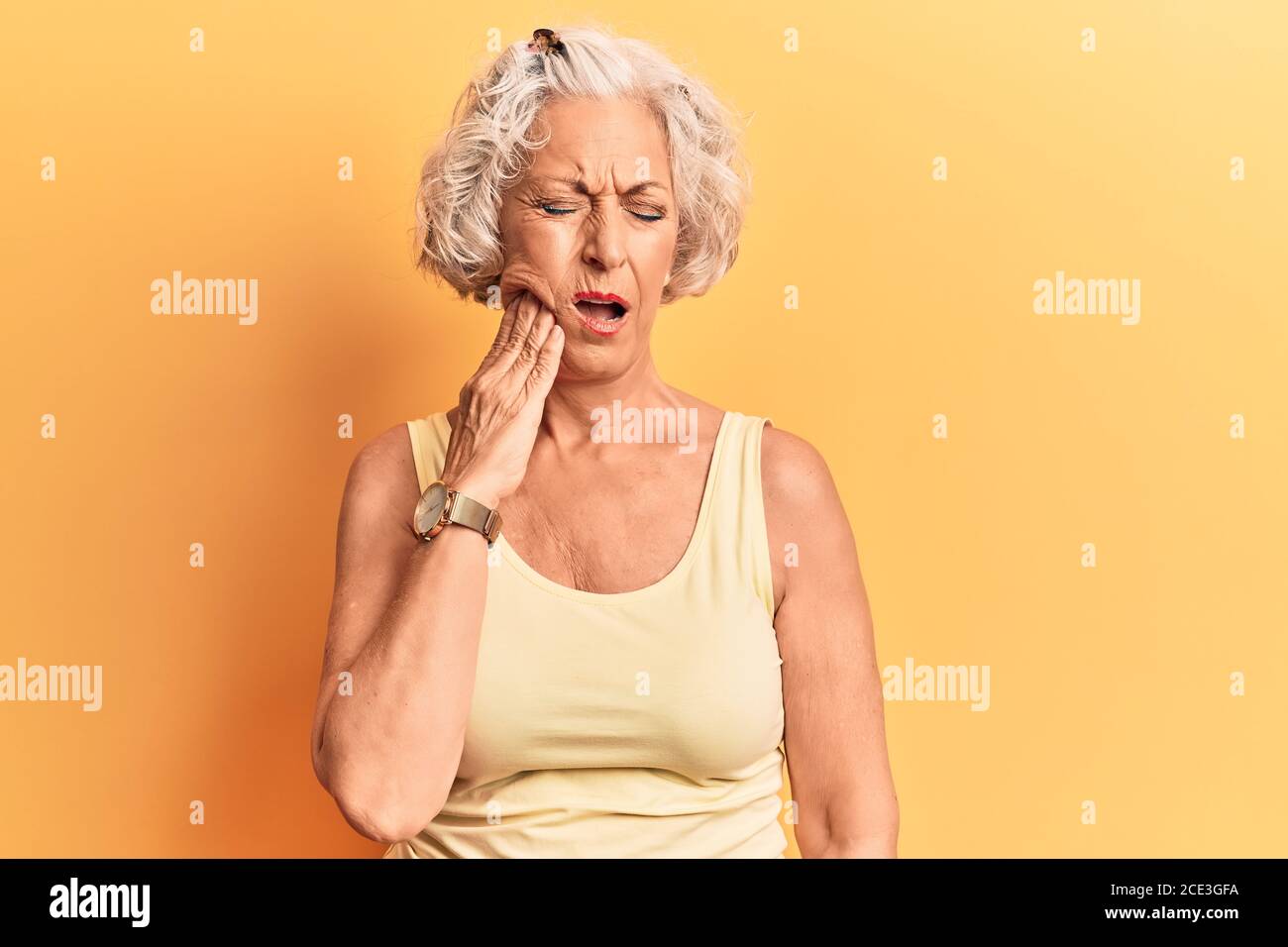 Senior grey-haired woman wearing casual clothes touching mouth with ...