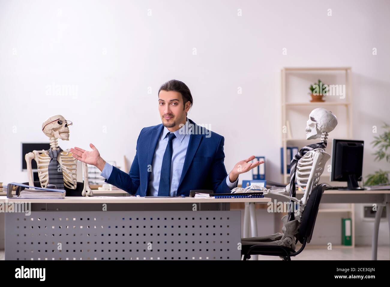 Young employee with skeletons in the office Stock Photo - Alamy