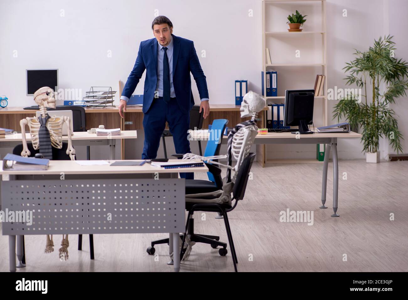 Young employee with skeletons in the office Stock Photo - Alamy