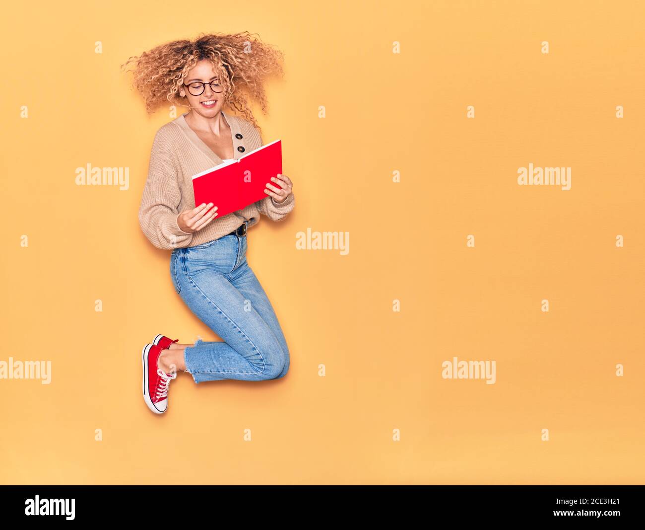Young beautiful curly student girl wearing glasses smiling happy ...
