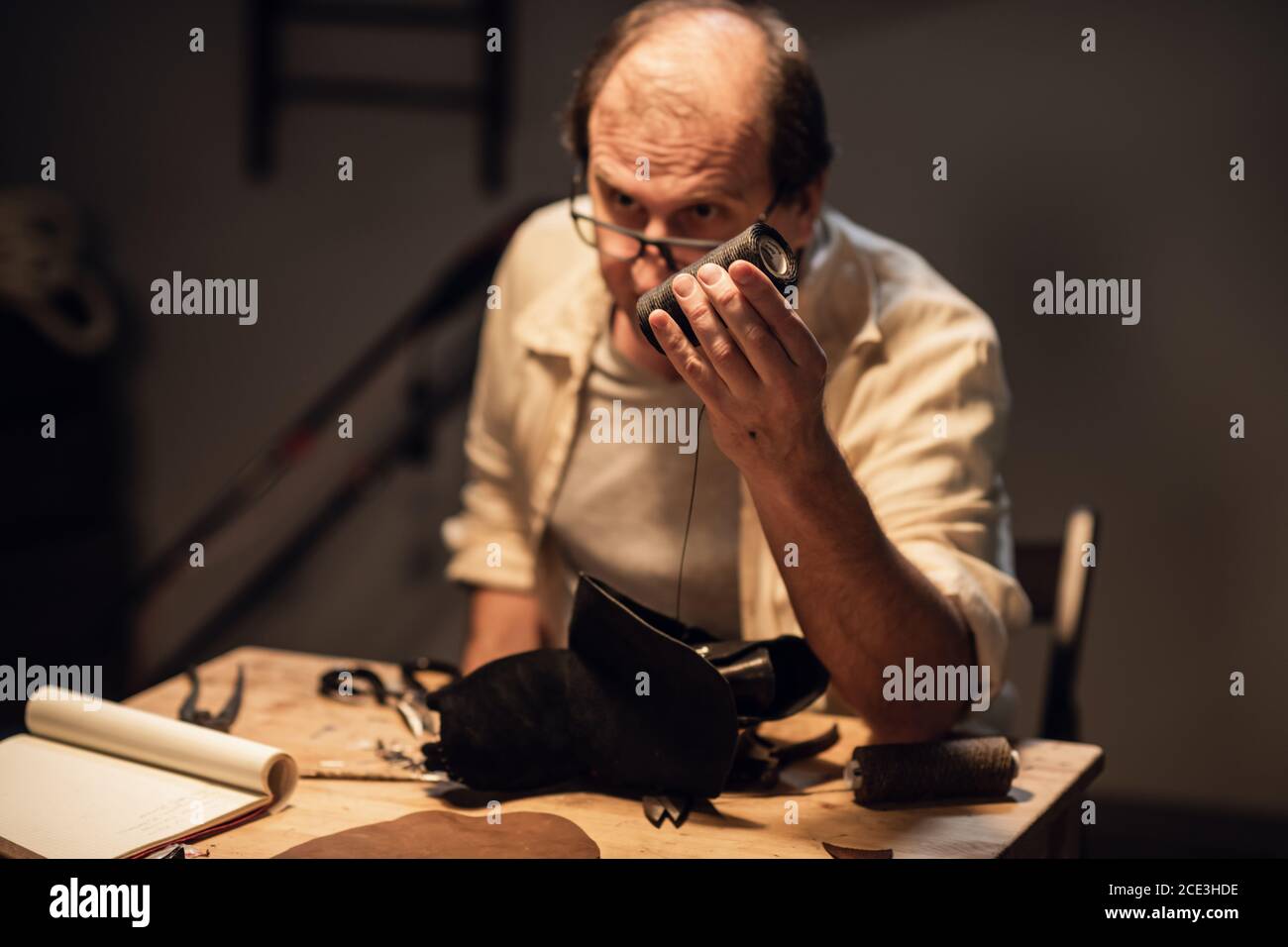 an experienced manual Shoe maker shows his students how to work with ...