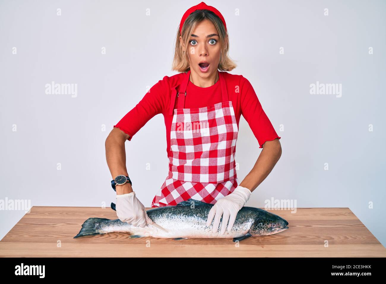 Beautiful caucasian woman fishmonger selling fresh raw salmon afraid ...