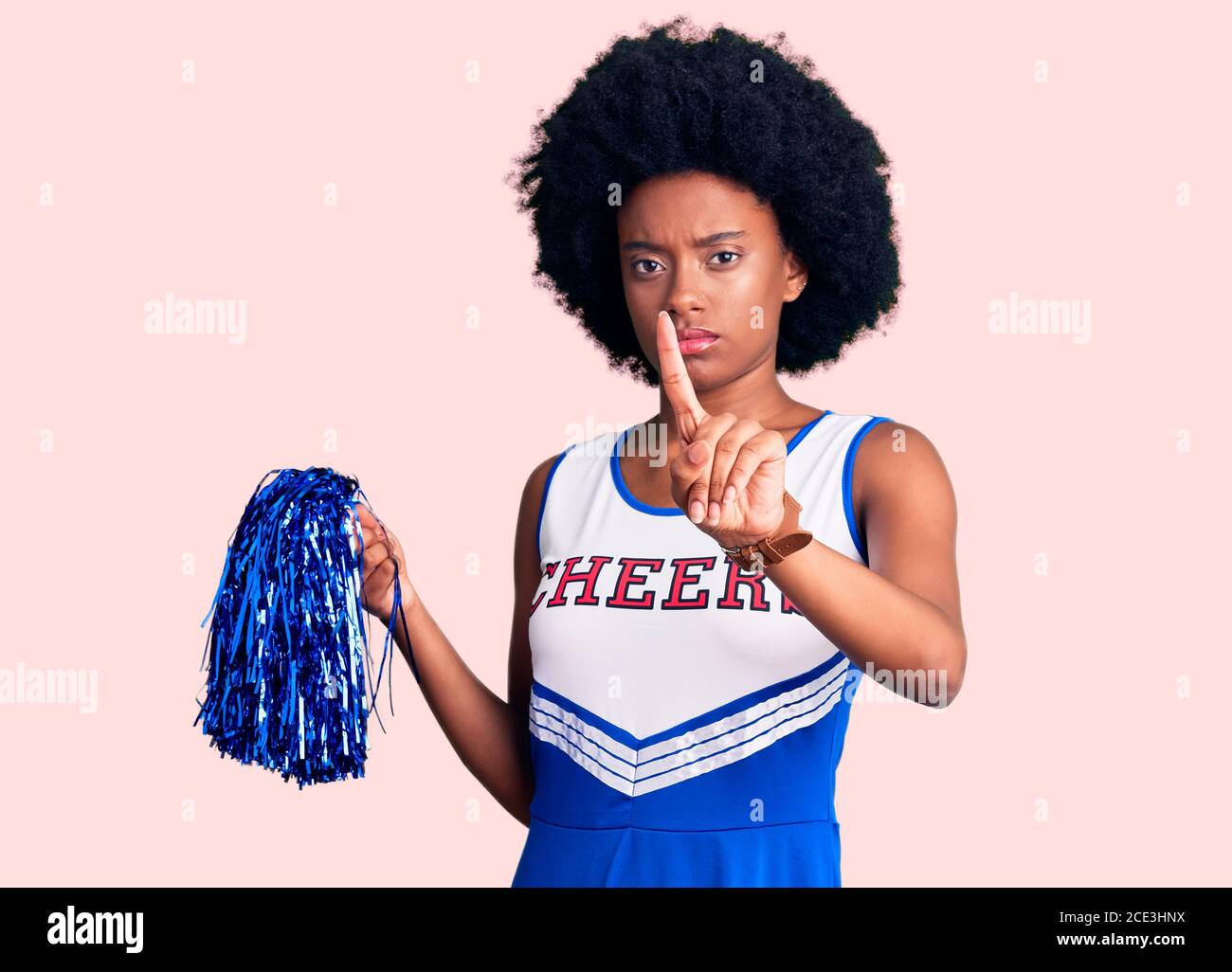 Young african american woman wearing cheerleader uniform holding pompom ...