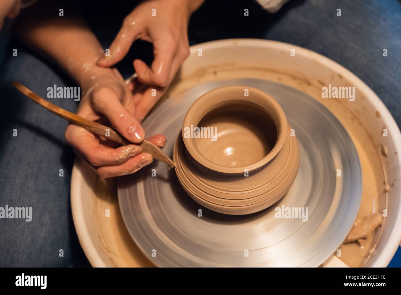 a master in a pottery workshop shows the technique of modeling a pot on ...