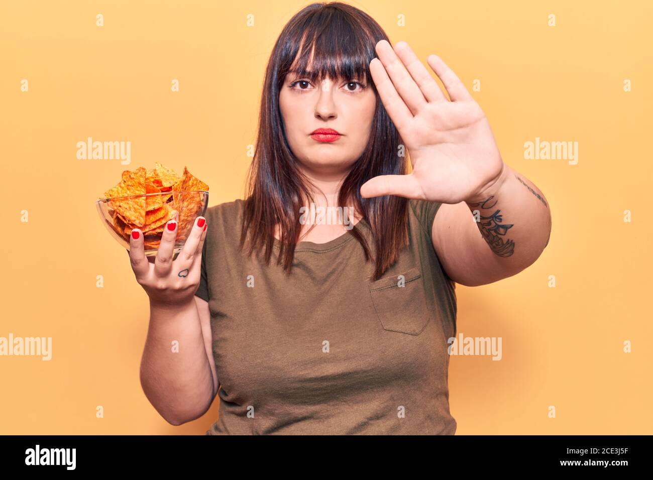 Young plus size woman holding nachos potato chips with open hand doing ...