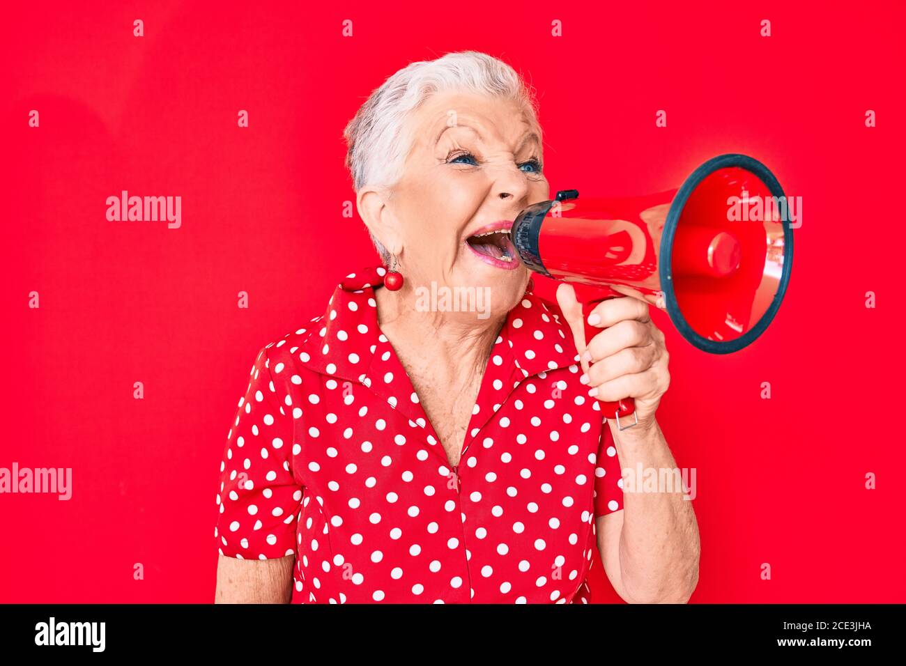 Senior beautiful grey-haired woman screaming using megaphone over ...