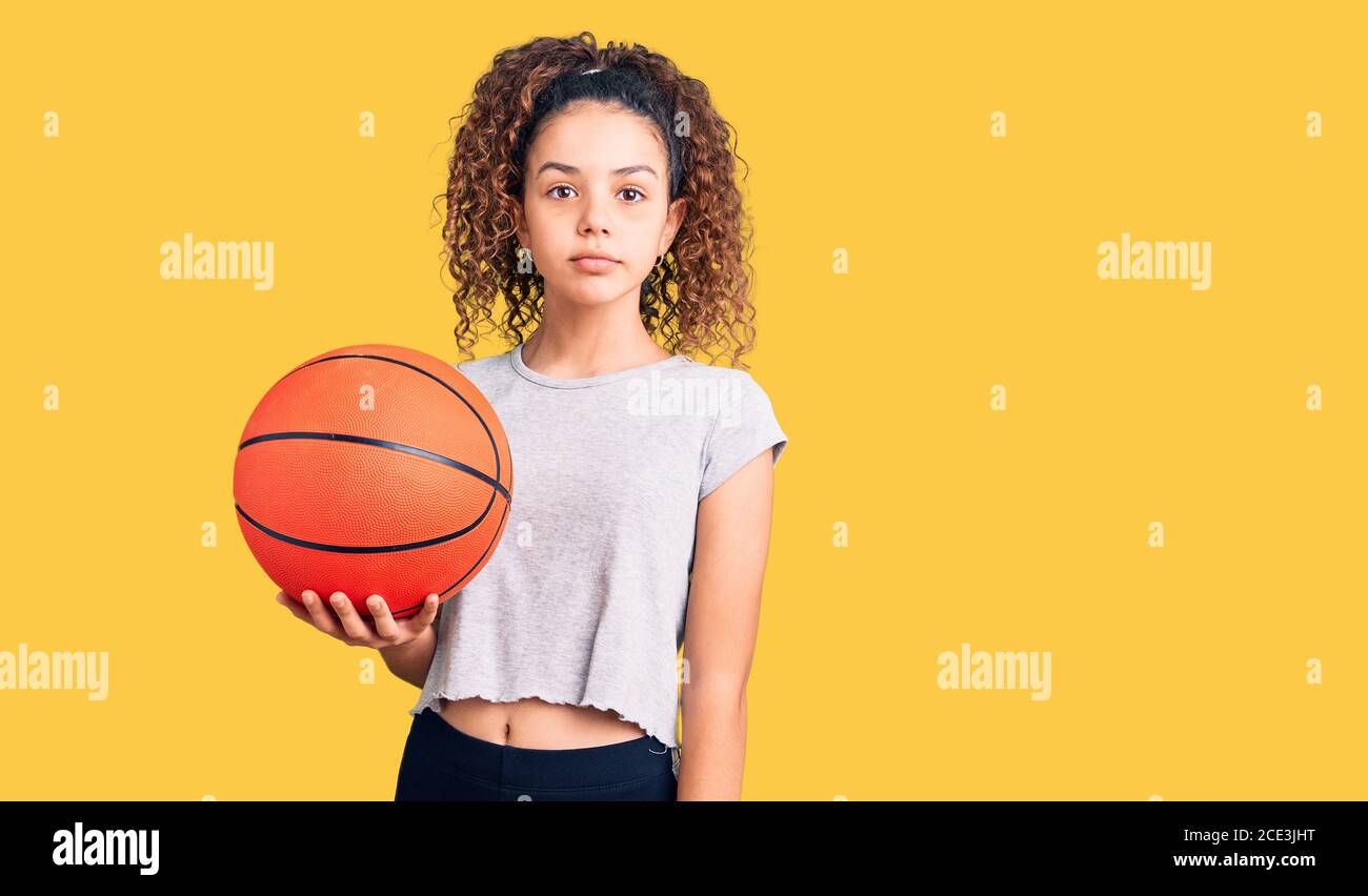 Beautiful kid girl with curly hair holding basketball ball thinking ...