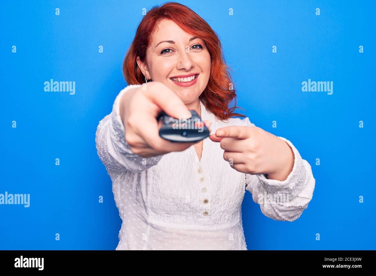 Young beautiful redhead woman changing television channel using tv ...