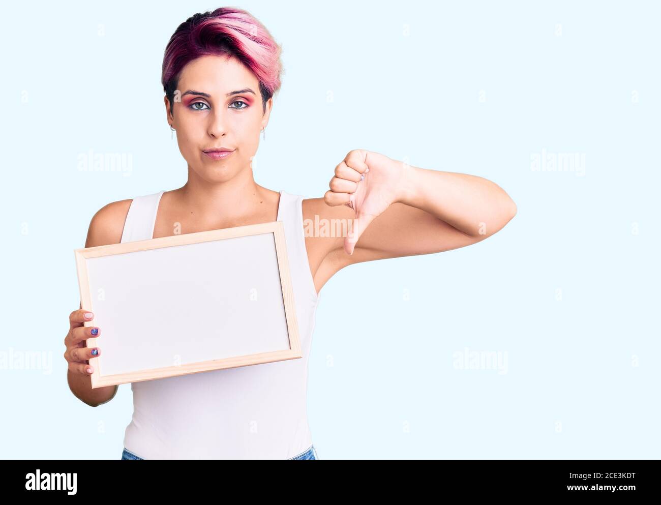 Young beautiful woman with pink hair holding empty white chalkboard ...