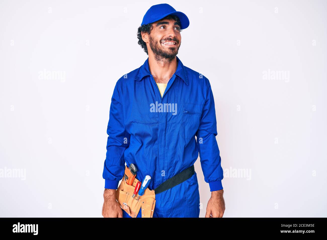 Handsome young man with curly hair and bear weaing handyman uniform ...